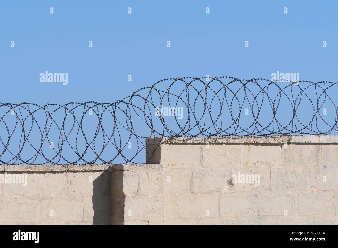 Concrete block wall with barbed wire at a protected area. Security ...