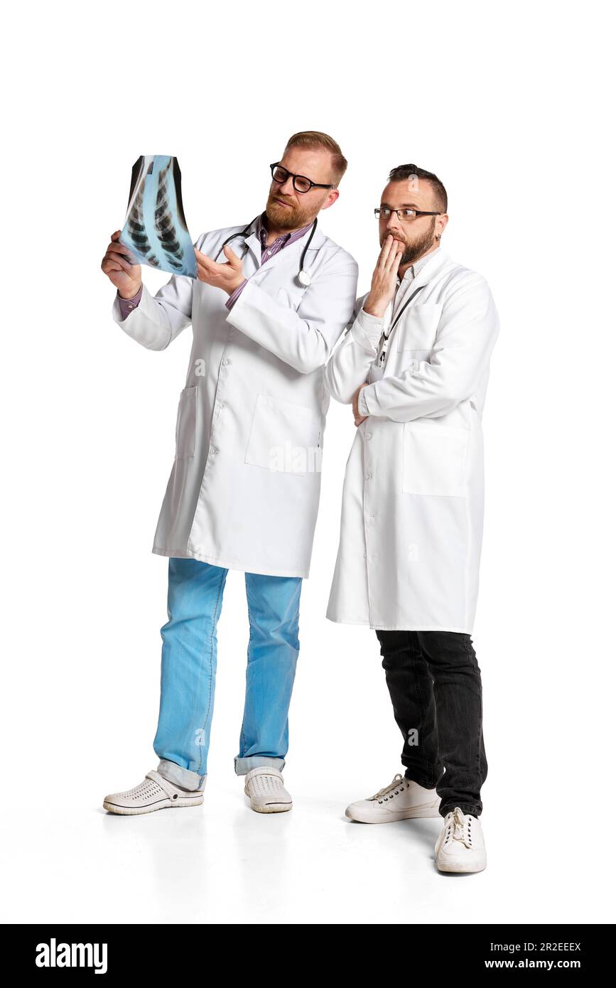 Two men, doctors in white lab coat looking at x-ray scan, checking ...