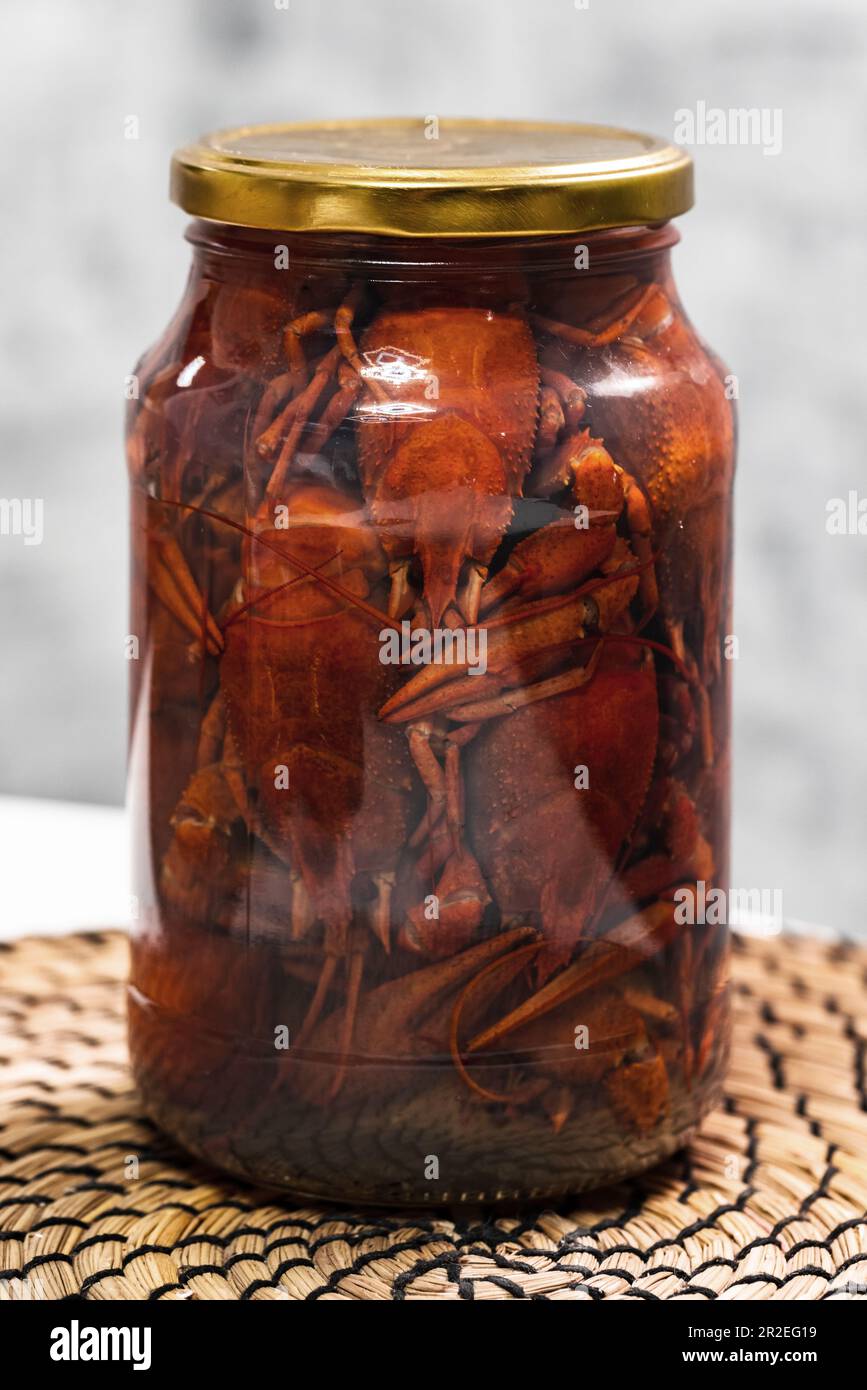 Glass jar of red pickled crayfish, close up vertical photo with ...