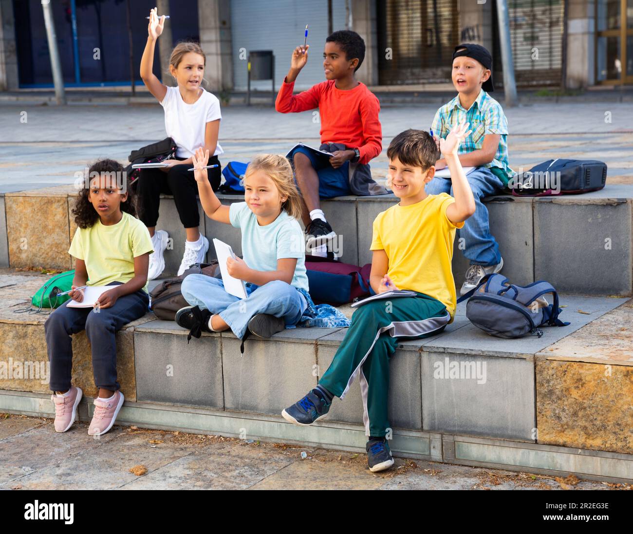 Schoolchildren with hands raised during lesson outside school Stock ...