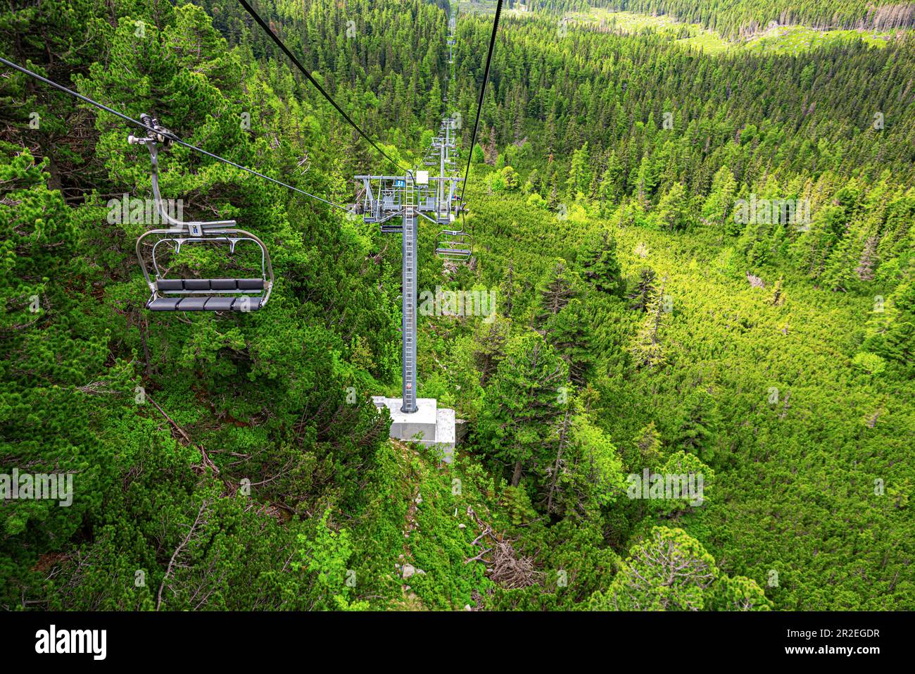 Tourist double lift above the forest on the mountain slope Stock Photo ...