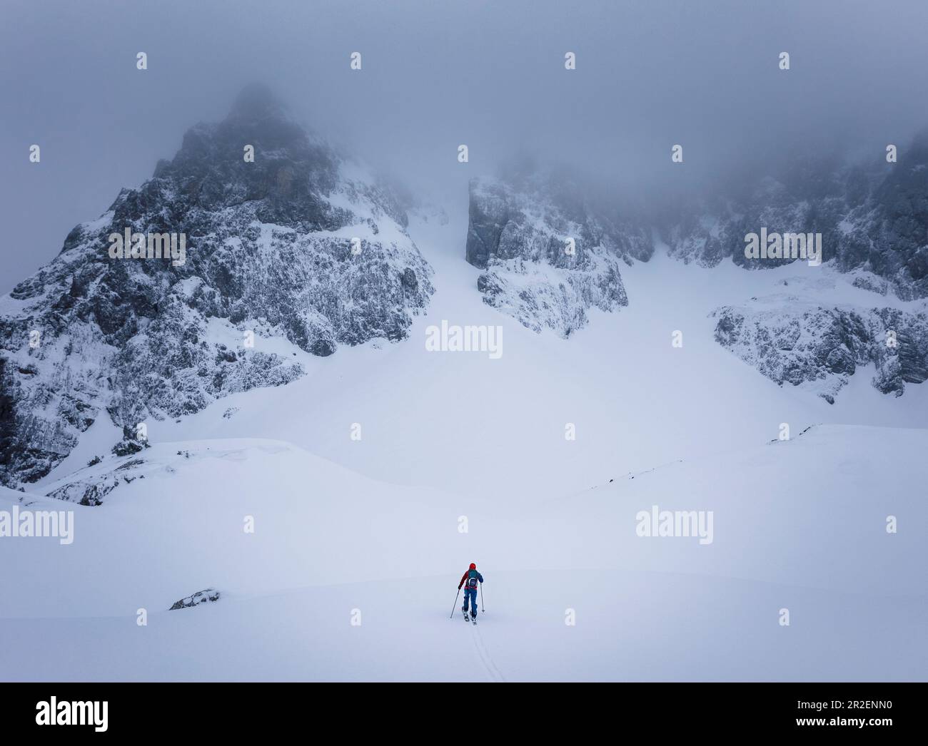 Ski tourers ascending to a steep channel with poor visibility and ...