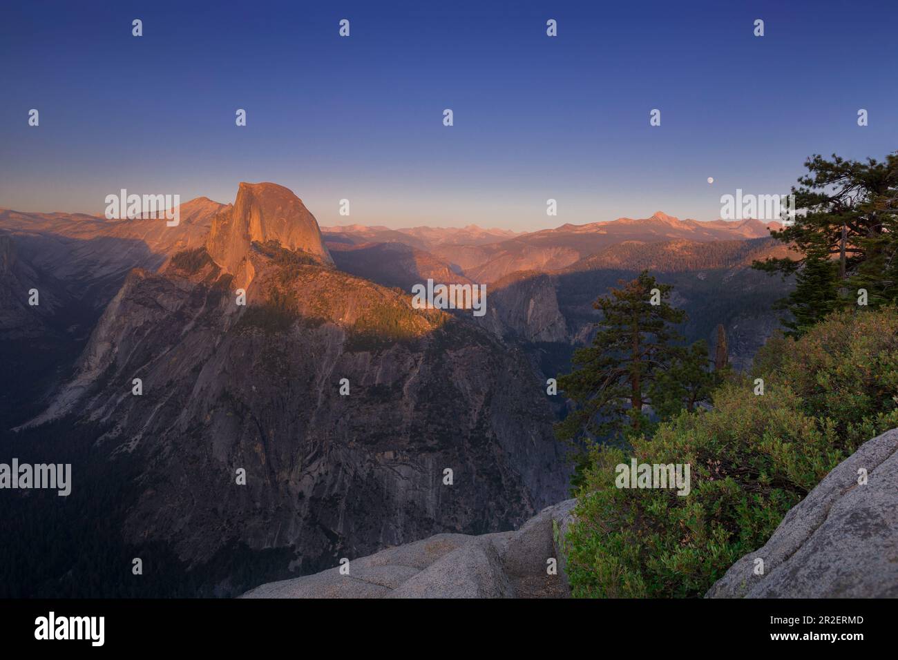 Half Dome in Yosemite National Park lit up in summer sunset, moon on ...