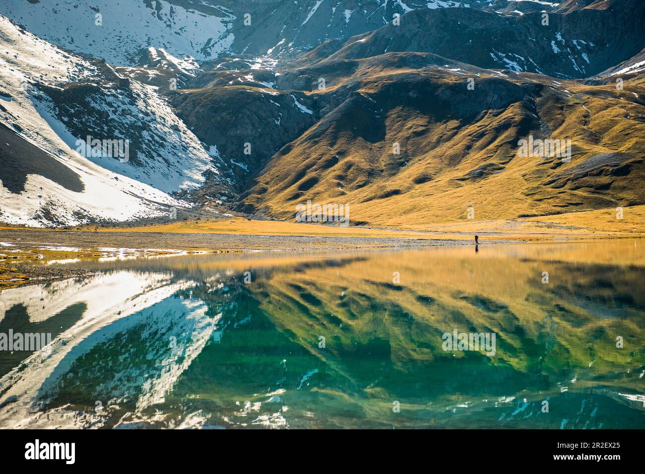 Hikers and Graubünden mountains are reflected in the mountain lake. Lai ...