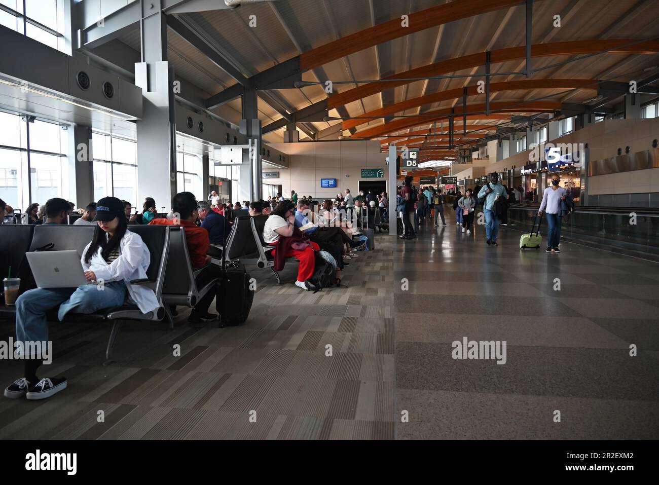 Travelers walk the long hallway between gates in Terminal Two of ...