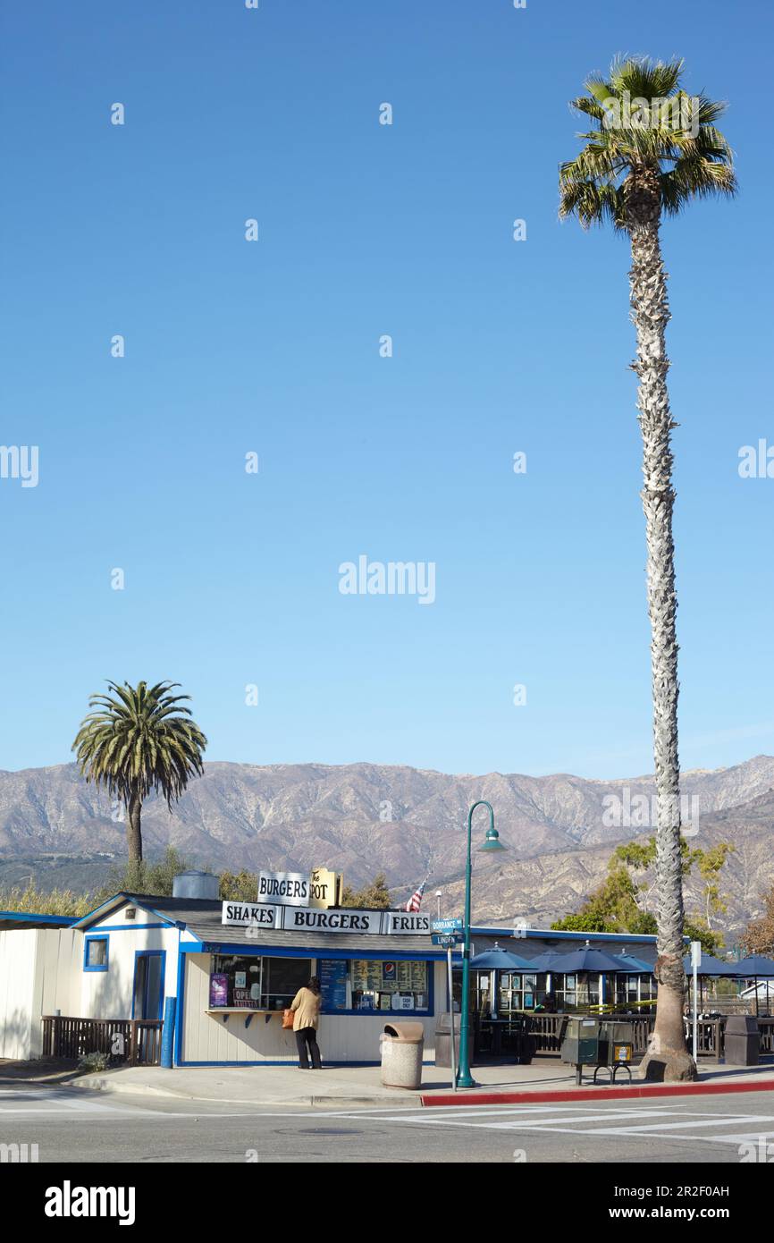 Burger restaurant with palm trees against mountains and blue sky ...