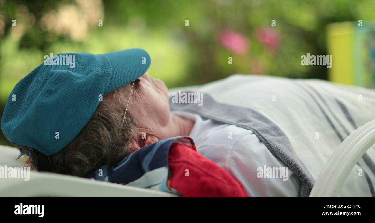 Man sleeping lying down outside. Older retired person napping outdoors ...