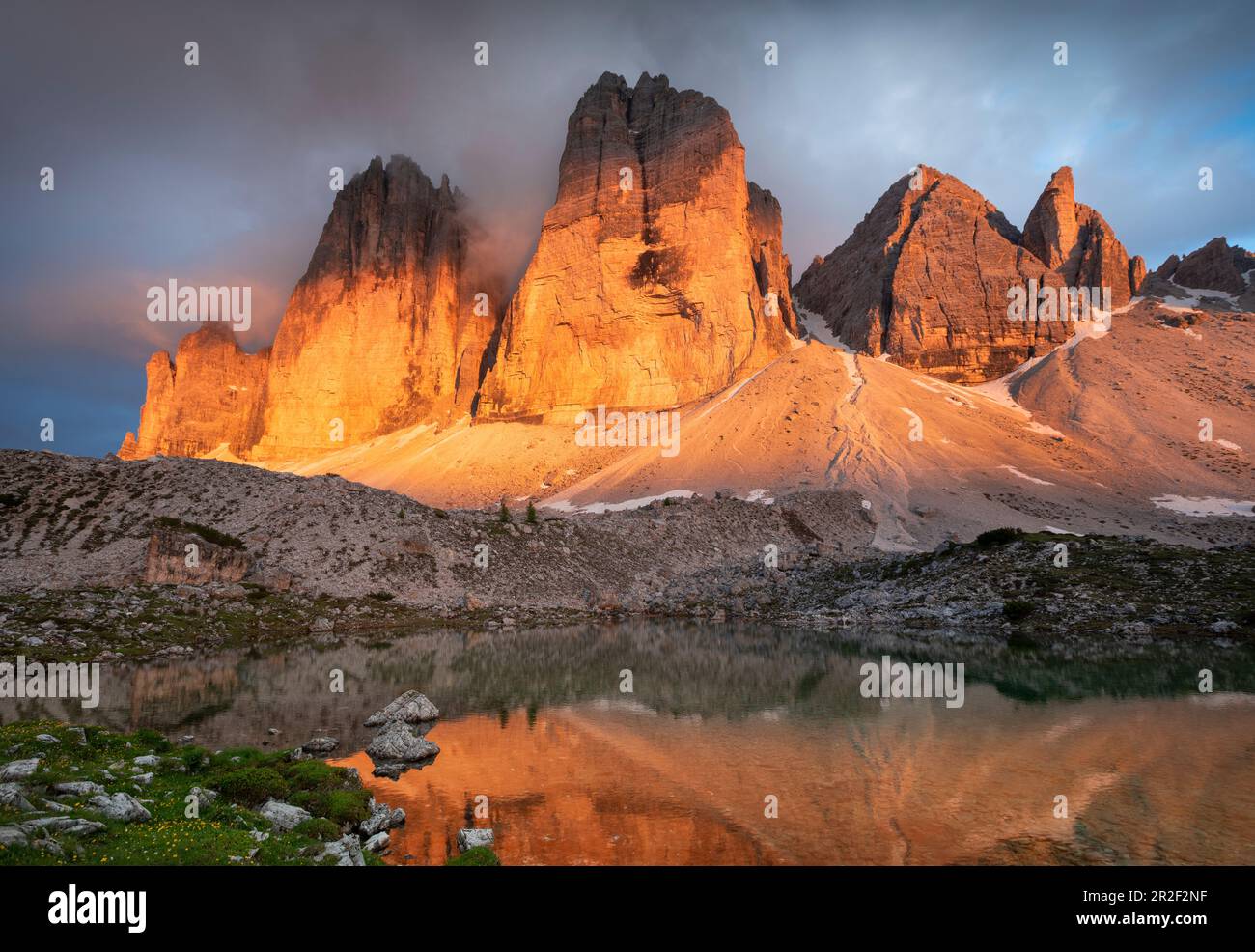 Dramatic Alpine glow of the Three Peaks with reflection in mountain ...