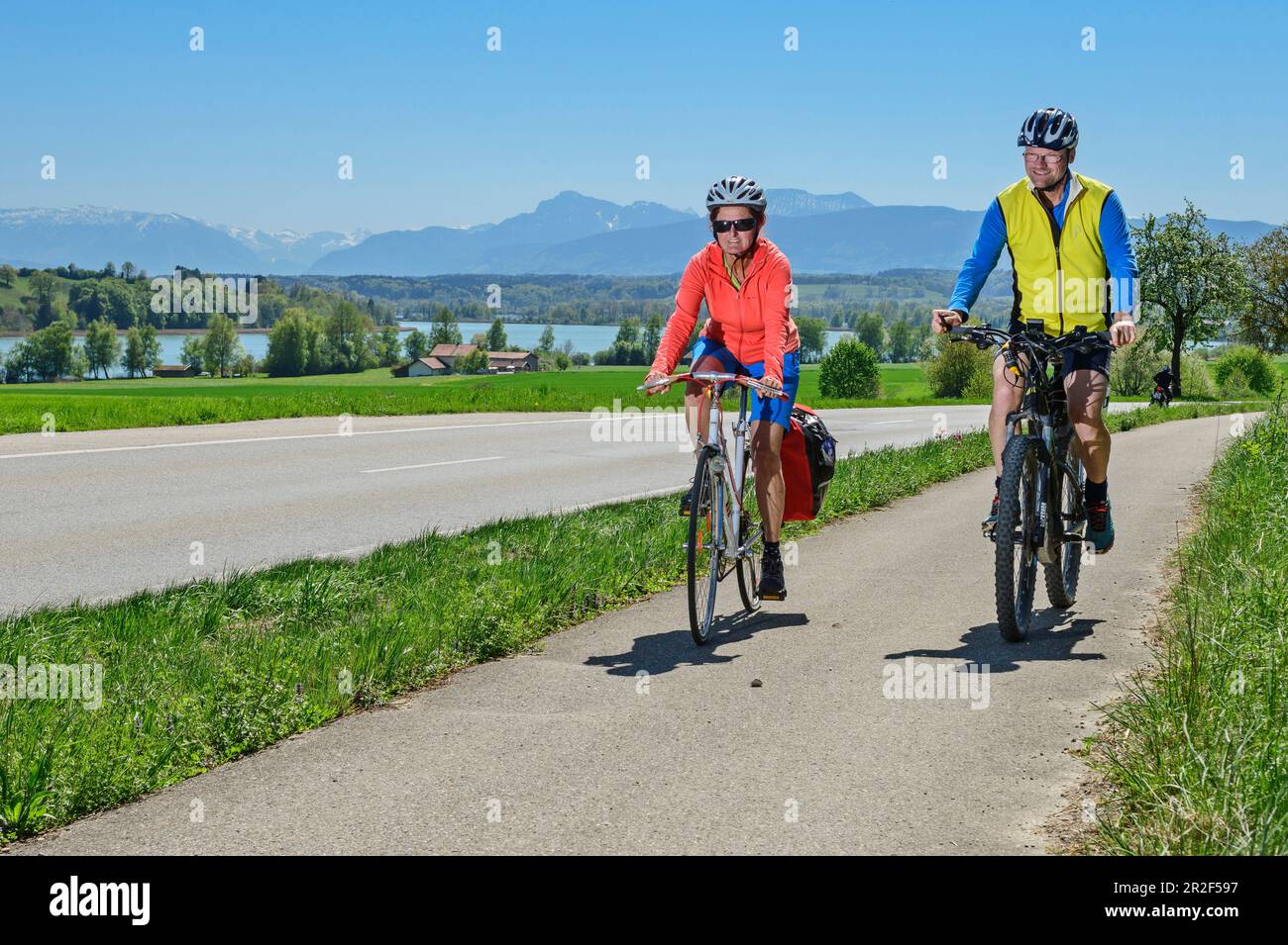 Woman and man cycling, Tachinger See and Chiemgau Alps in the ...