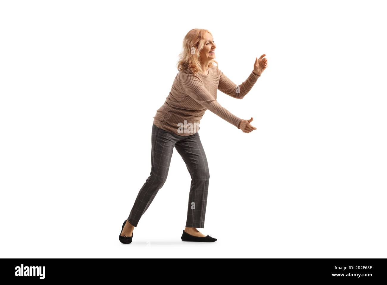 Full length shot of a cheerful woman trying to catch something isolated ...