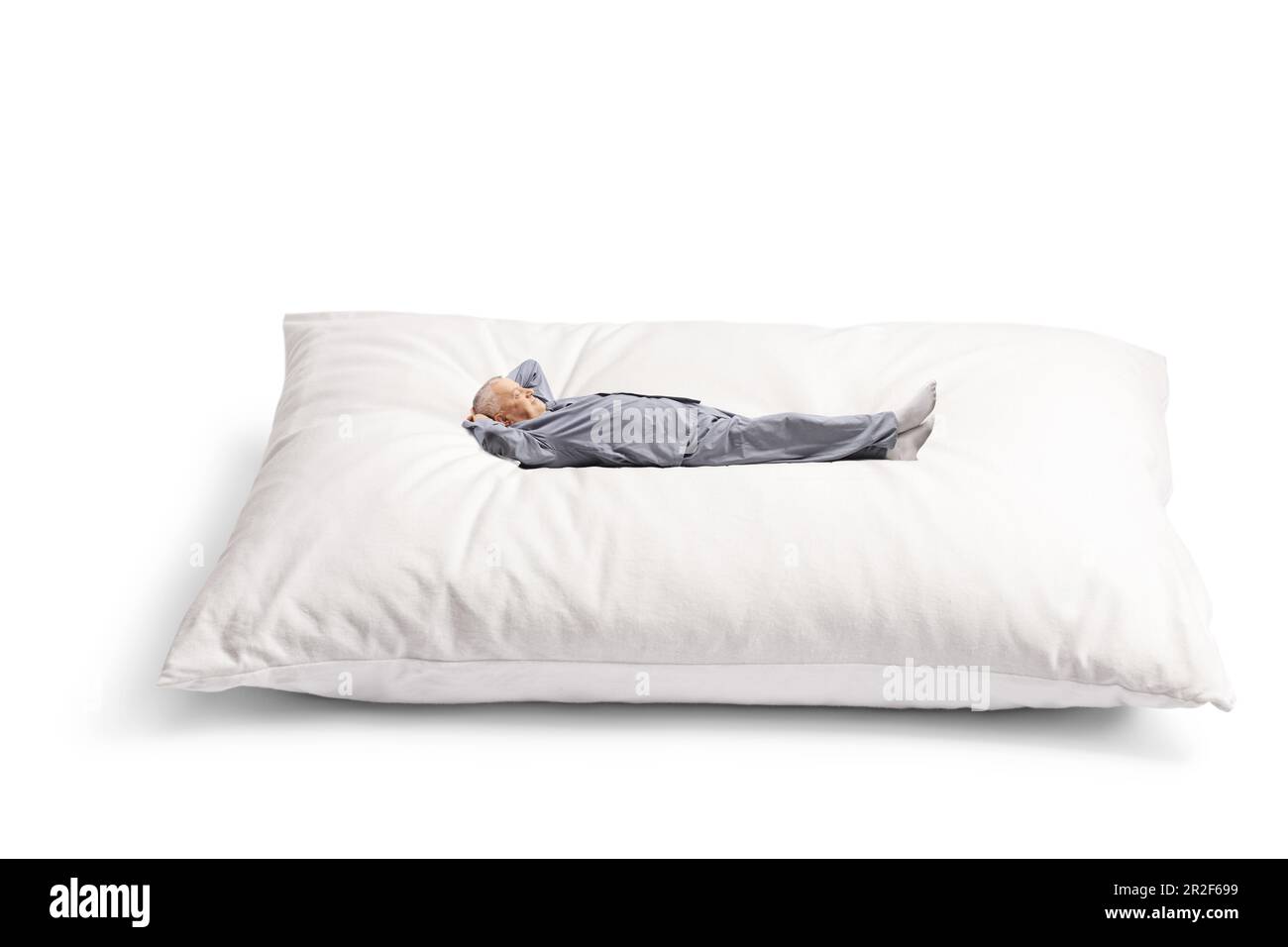Mature man in pyjamas lying on a big pillow isolated on white ...