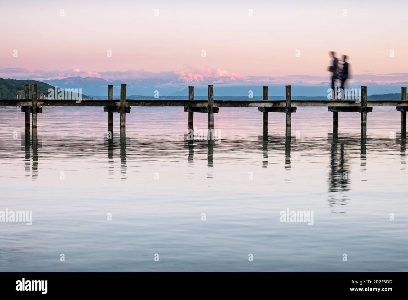 View of a jetty on Lake Starnberg at sunset, in the background the Alps ...