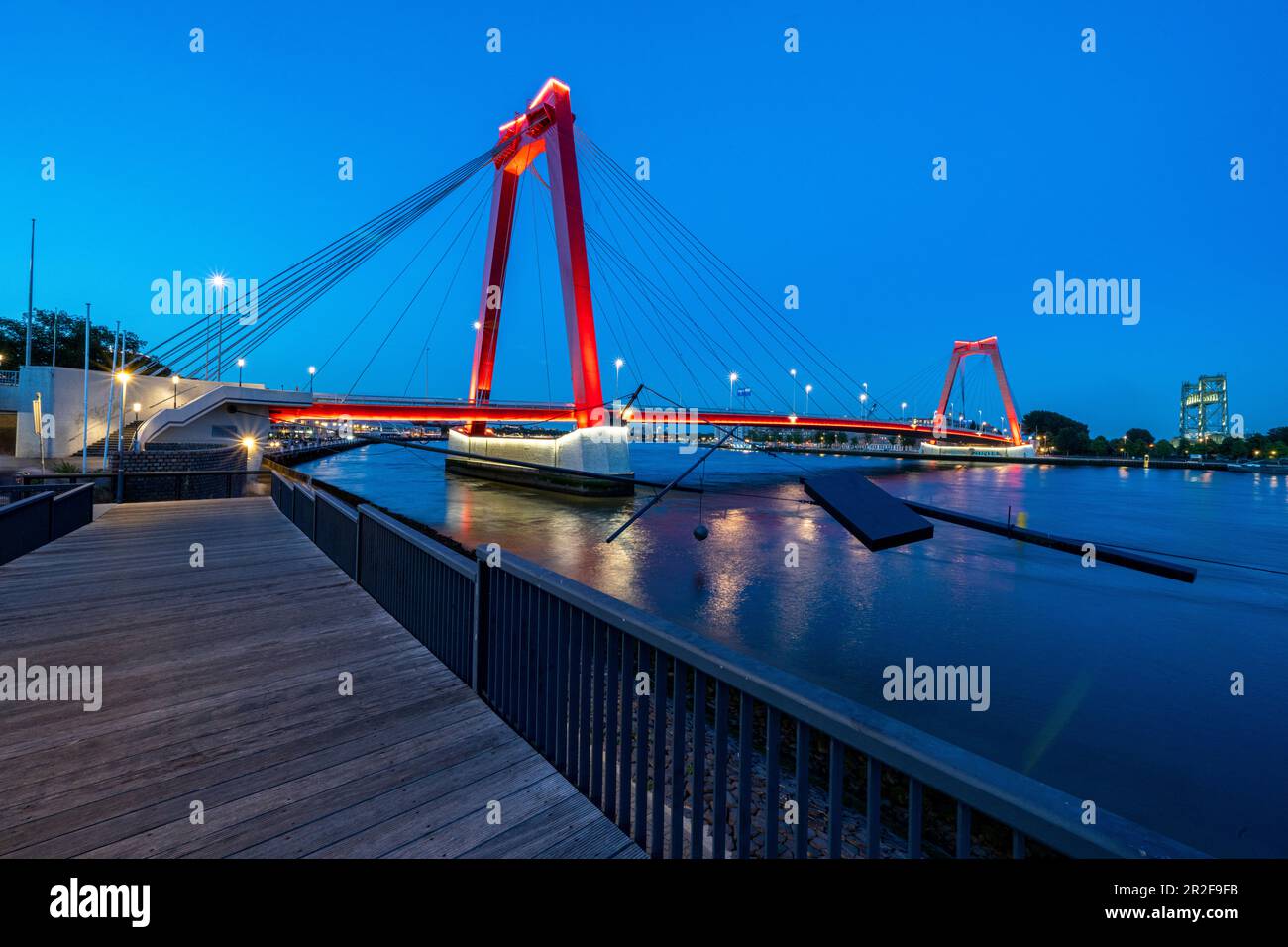 Illuminated, red Willemsbrücke during the blue hour, with plank path ...