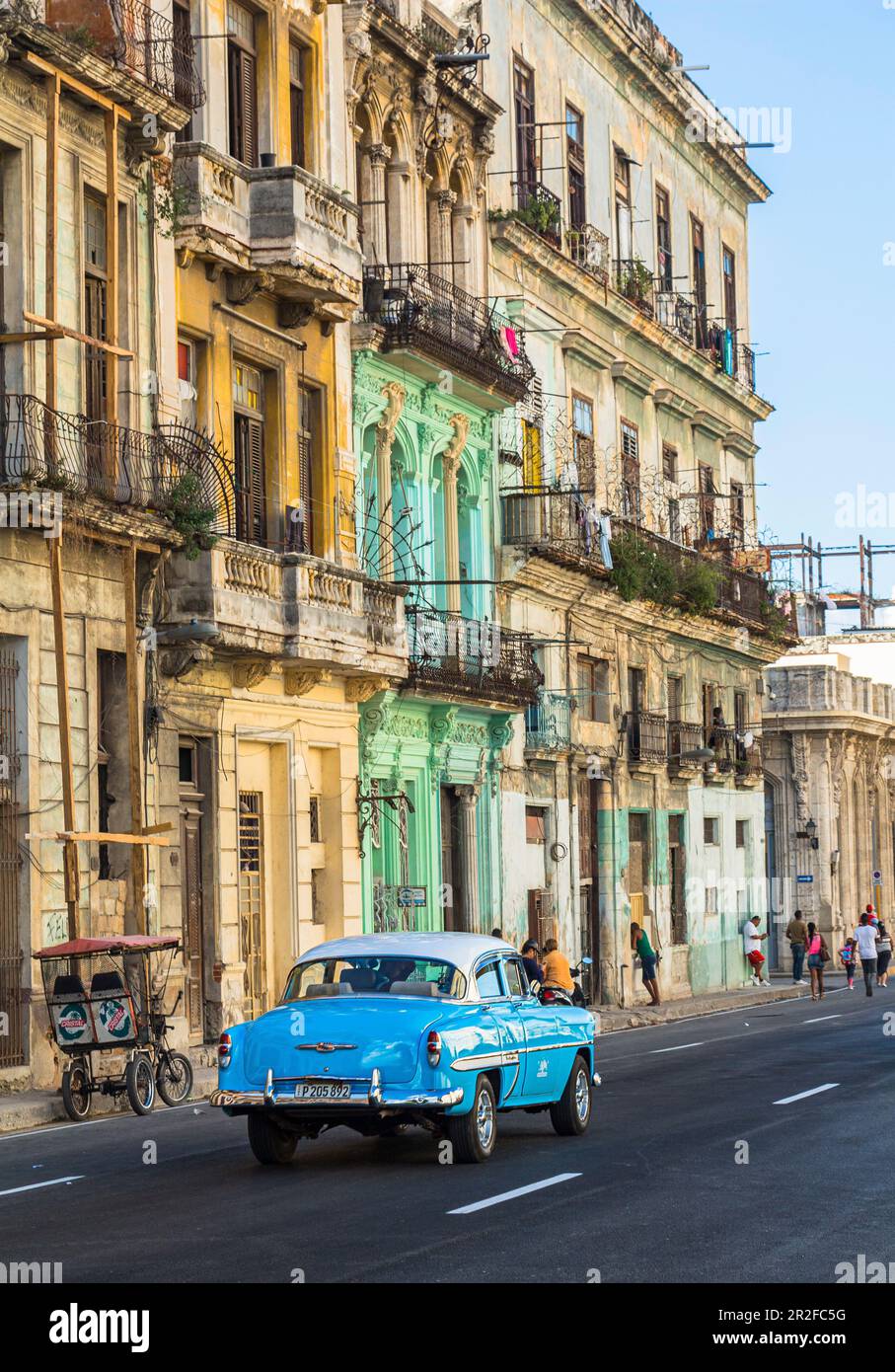 Vintage car drives through Cuban street with old, colorful colonial ...
