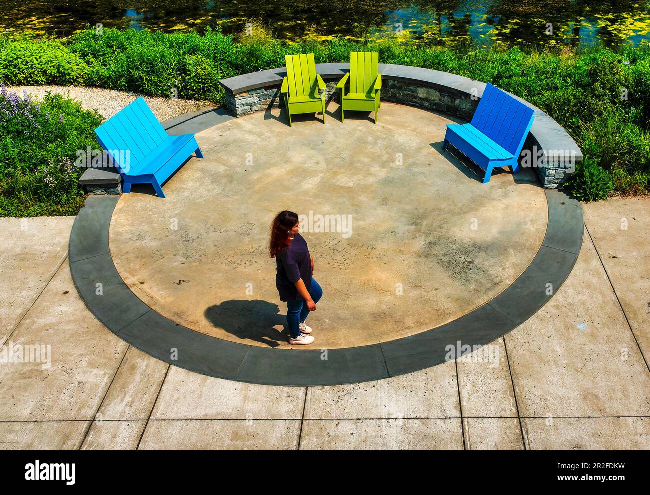 Woman walking past patio seating in a circle Stock Photo - Alamy