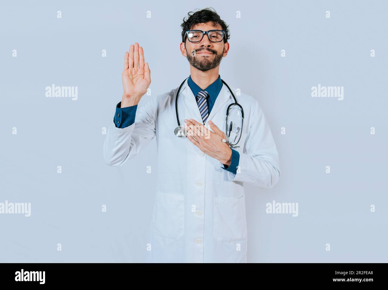 Handsome doctor making oath and promise isolated. Doctor raising hand ...