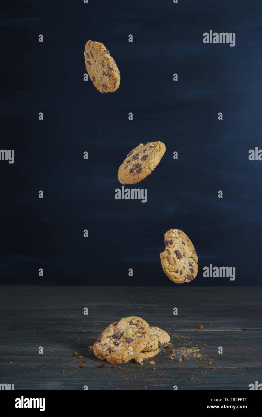 Chocolate cookies falling in a row on a wooden table with dark ...