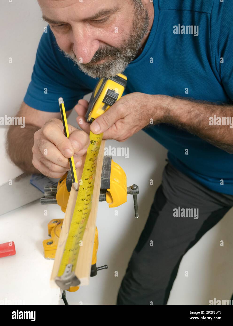 Front view of a bearded carpenter measuring a timber with a tape ...
