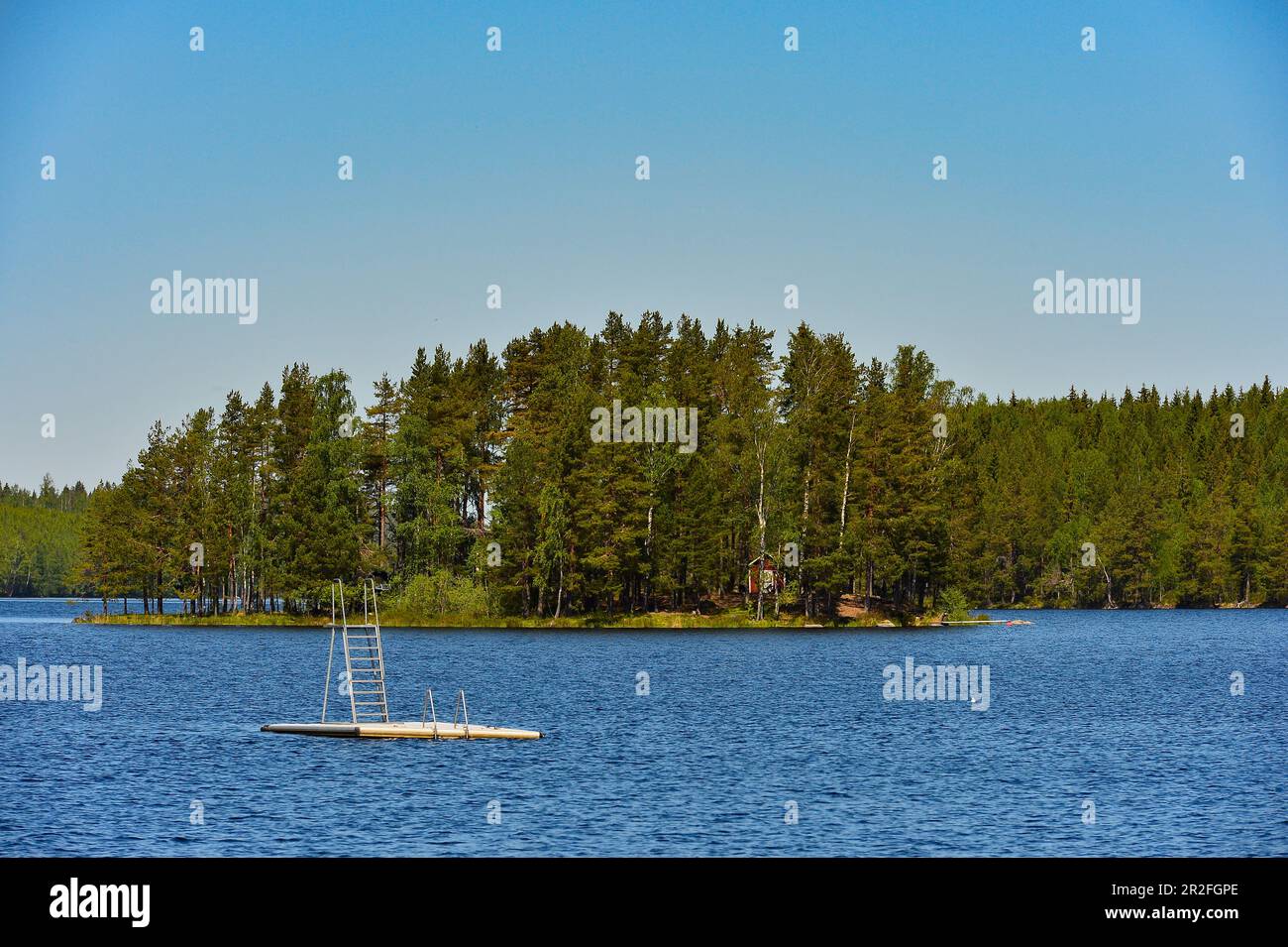 A small bathing platform in a lake with an island surrounded by forest ...
