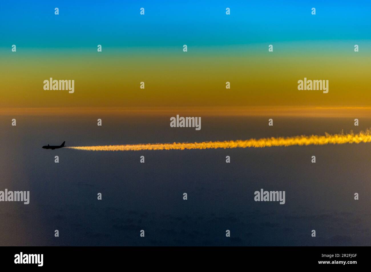 Airplane with contrails at dawn Stock Photo - Alamy