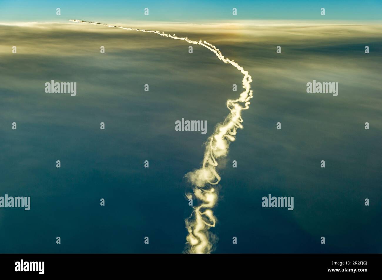 Airplane with long, thin and swirling contrails over cloud layer in a ...