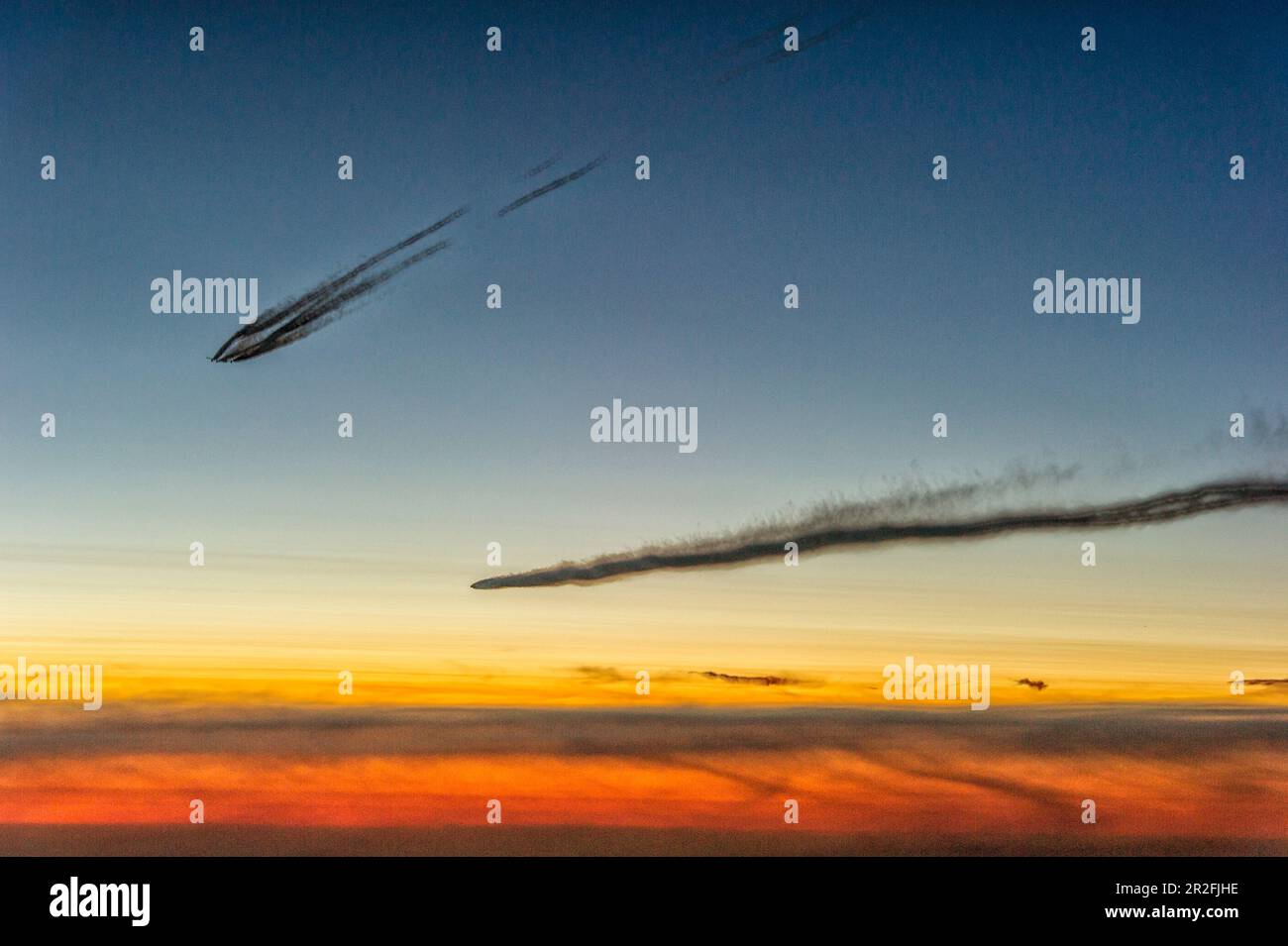 Airplanes with contrails just before sunrise Stock Photo - Alamy