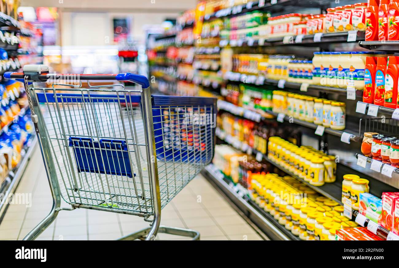 A shopping cart by a store shelf in a supermarket Stock Photo - Alamy