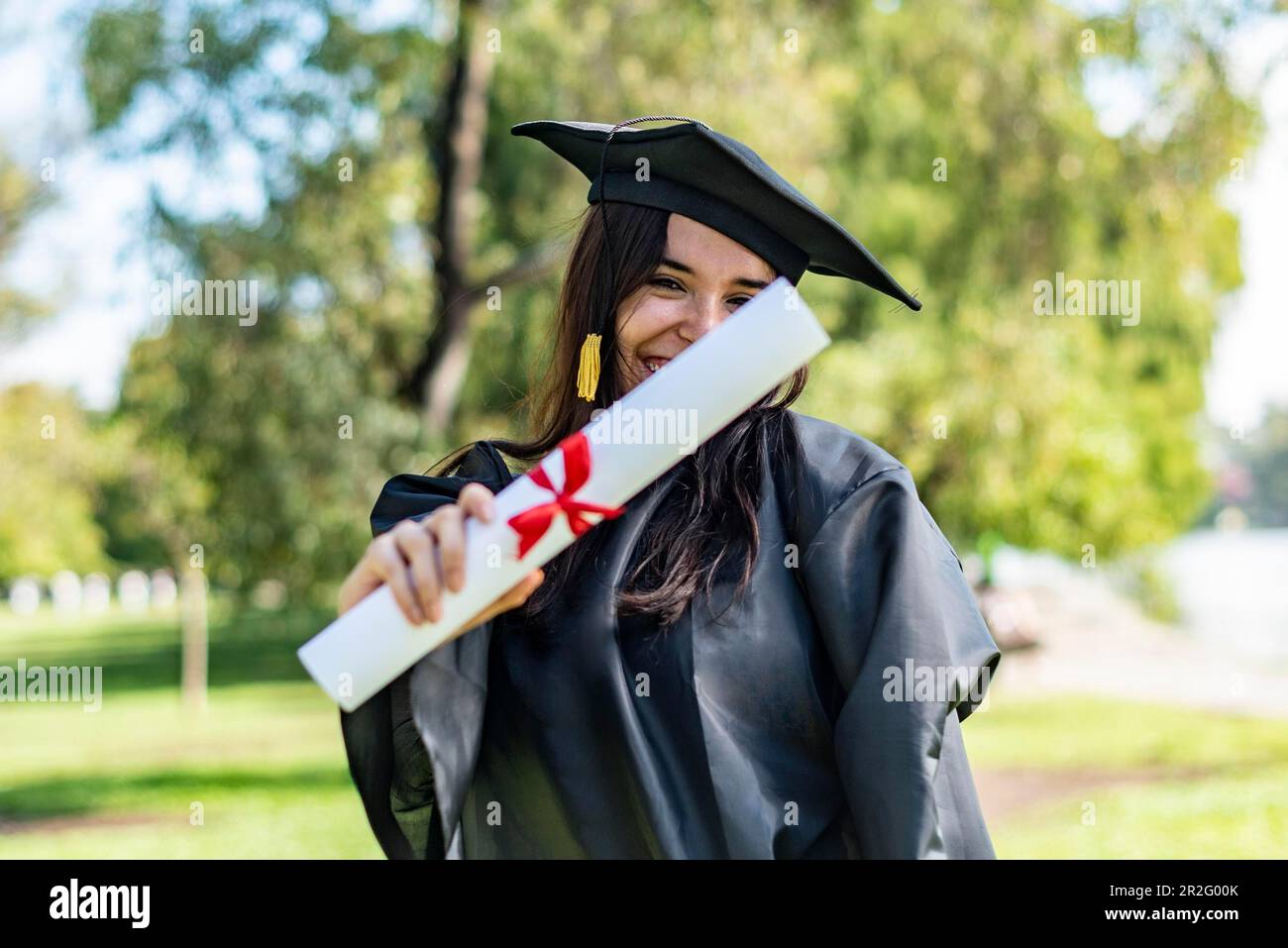 Happy caucasian graduated girl with long brown hair showing her diploma ...