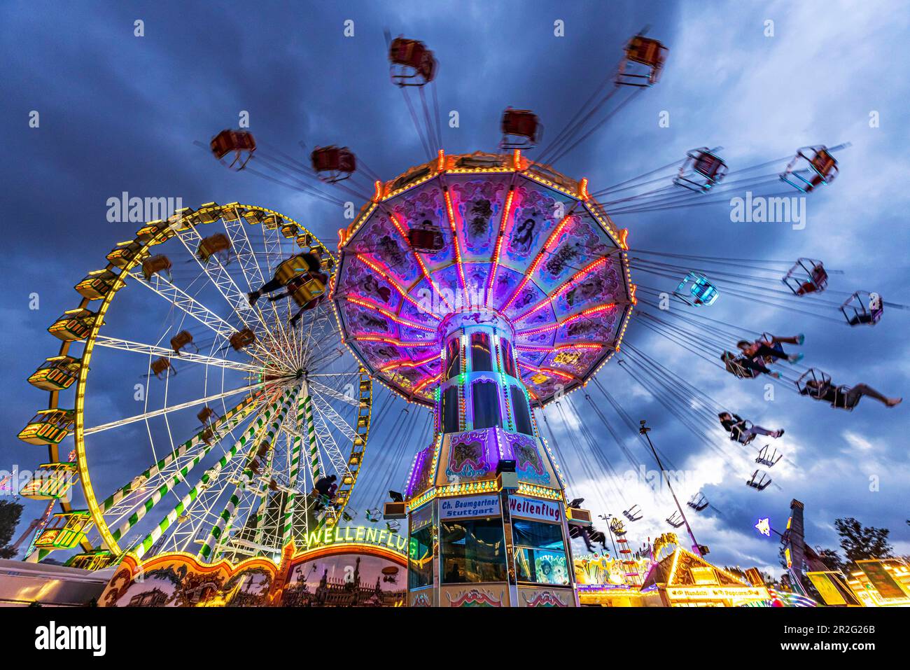 Ferris wheel and historic chain carousel in the evening, fairground ...