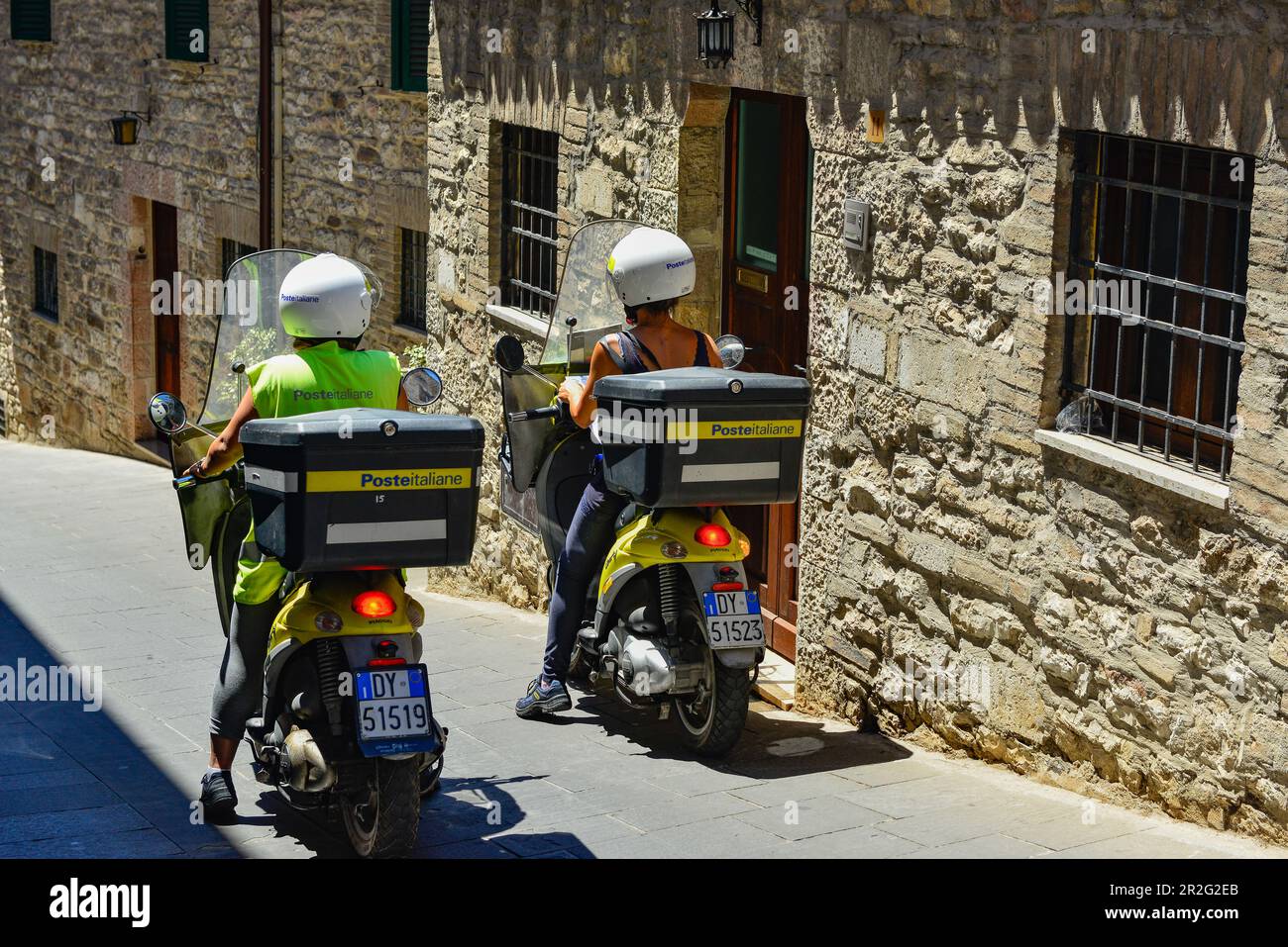 Two postmen on their scooters in the old town of Assisi, Italy Stock ...