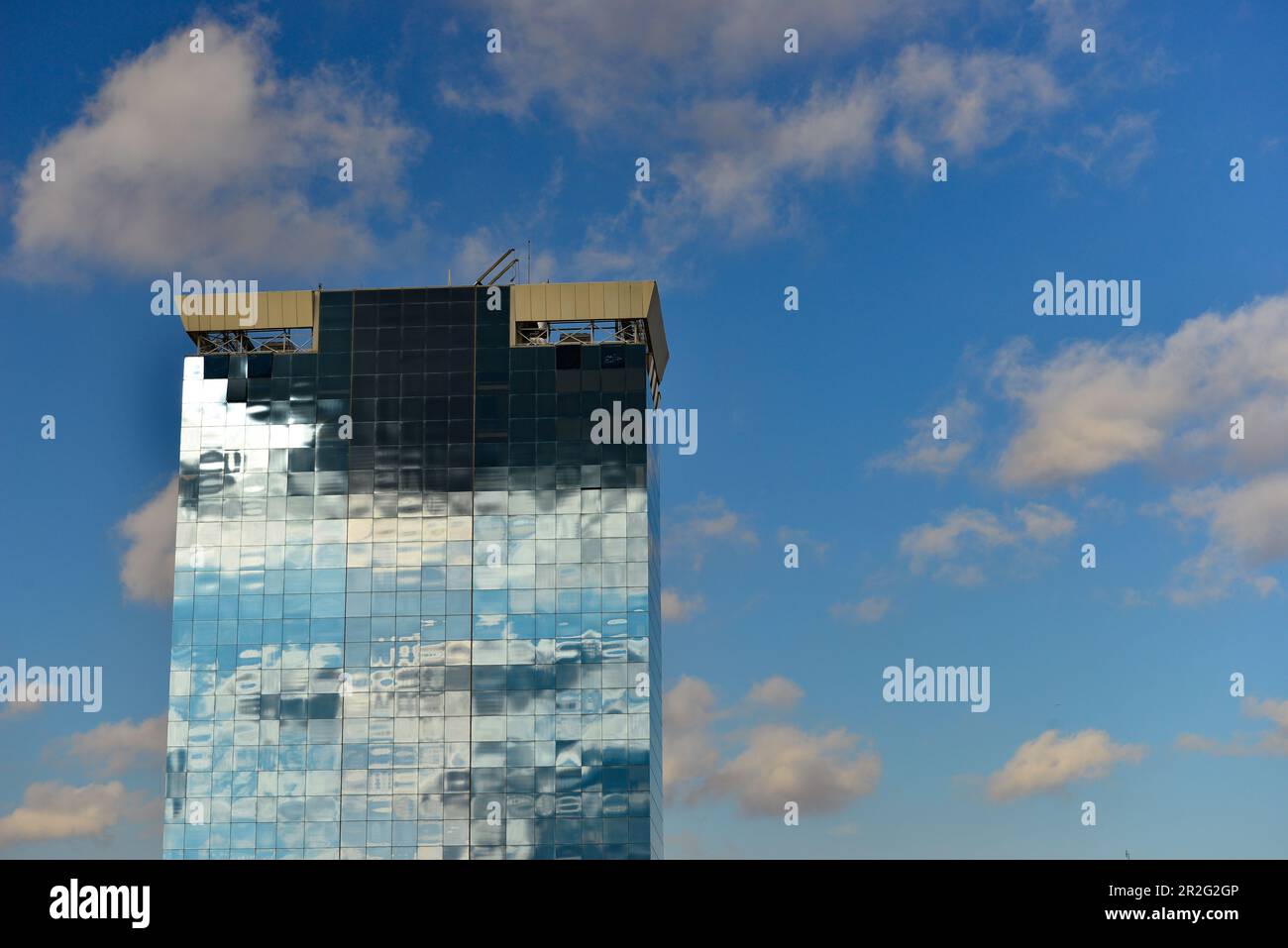 High-rise building with glass facade reflecting dark clouds and intense ...