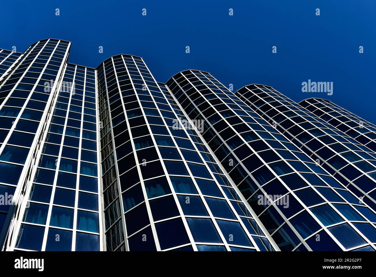 Futuristic office building with glazed facade against a deep blue sky ...