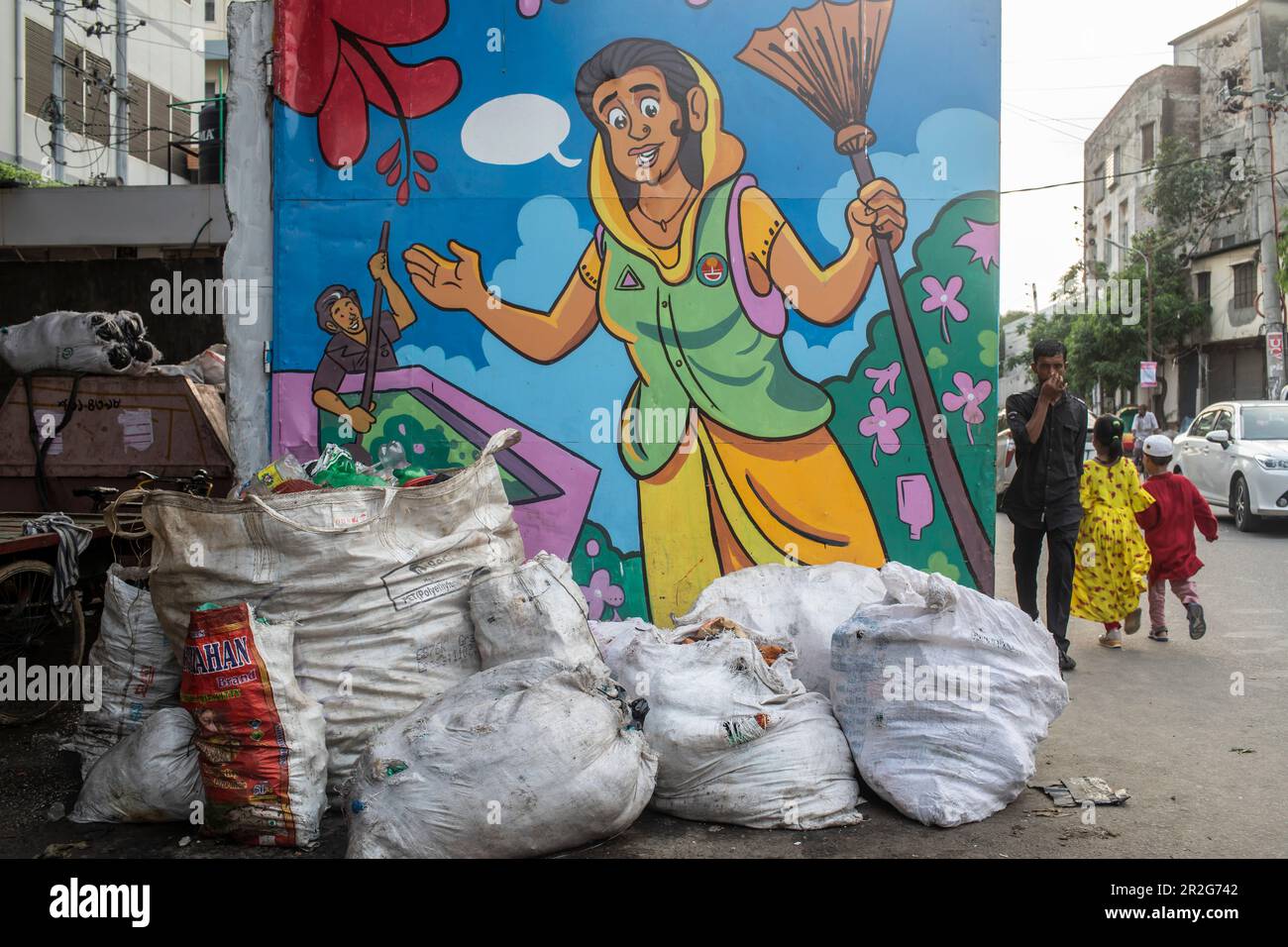 People walk past the graffiti in the waste transfer station of Mirpur ...