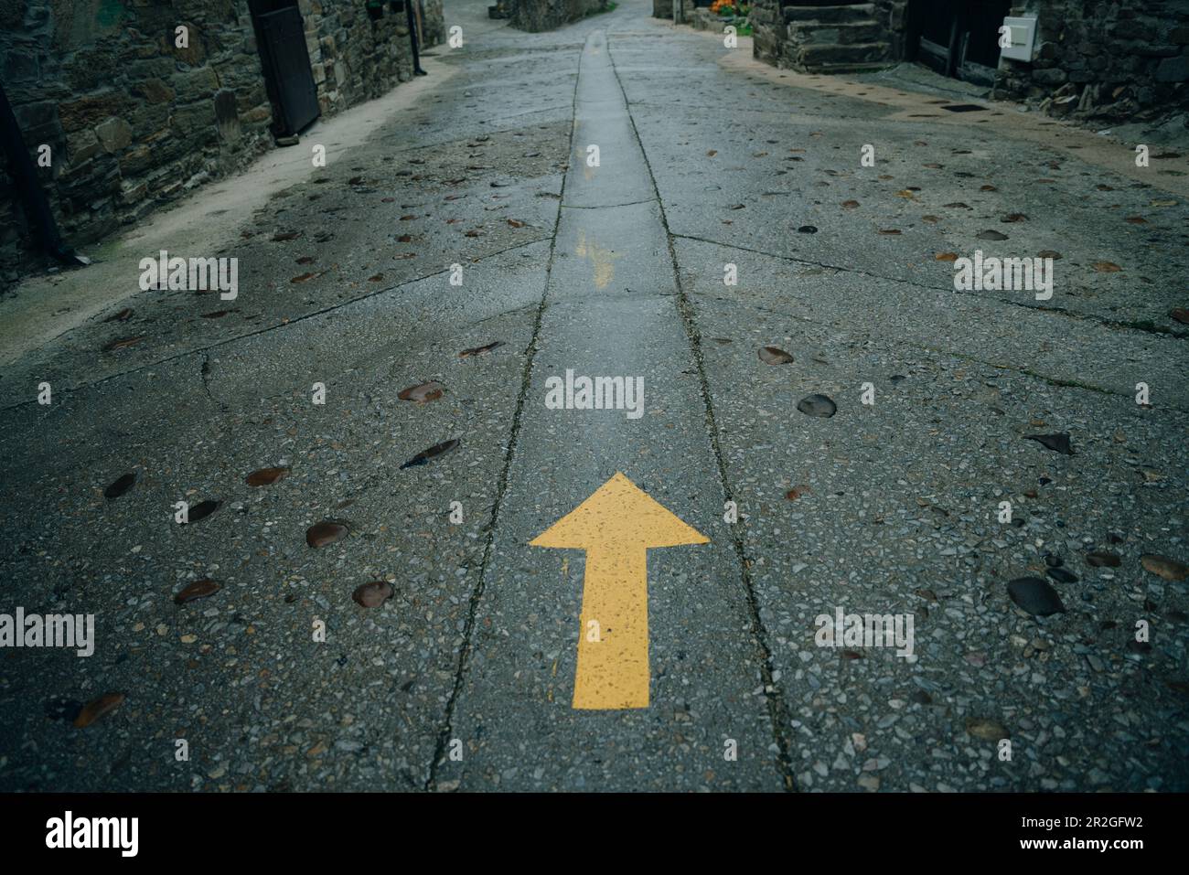 Yellow arrow painted in a road. Directional sign for pilgrims in Saint ...