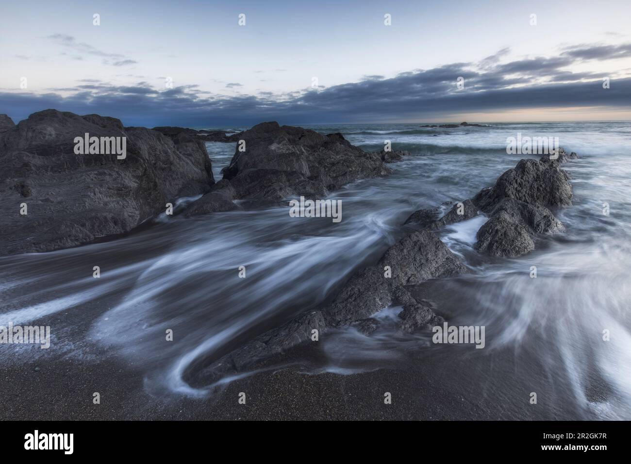 Surf laps rocks on Black Beach. Little Island Bay Beach, County Cork ...