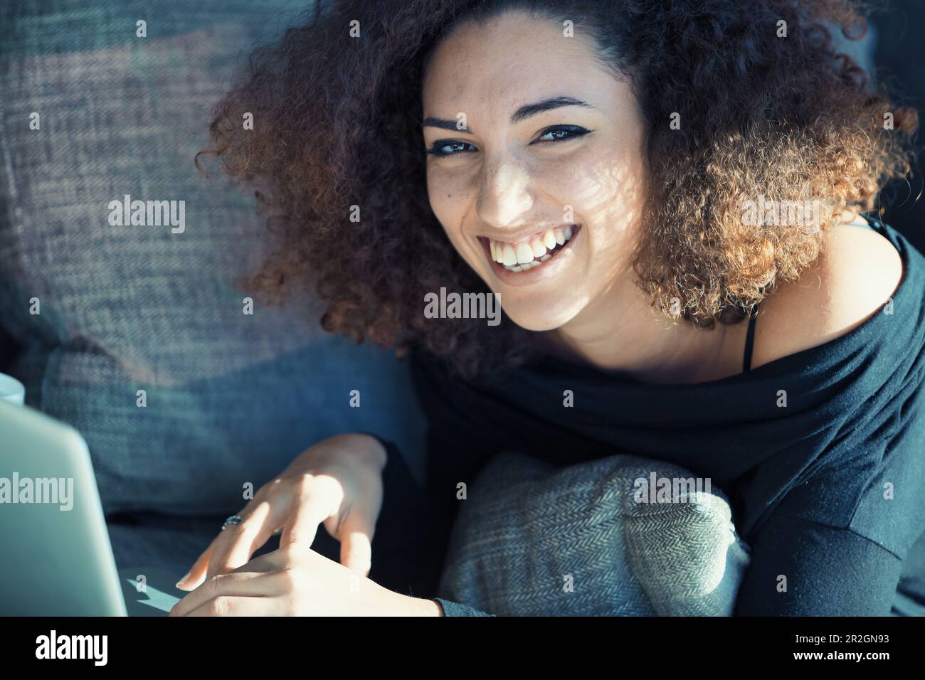 A radiant young woman with curly hair giggles heartily while engaging ...