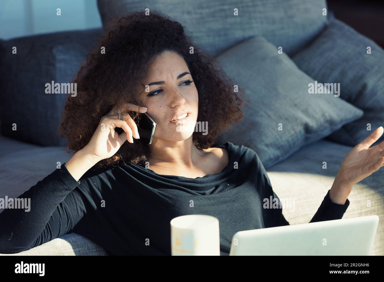 An ambitious young businesswoman conducts a phone call in her elegant ...