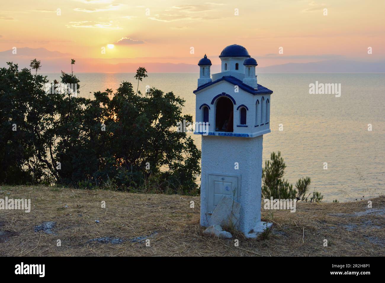 Traditional miniature church on sea shore against sunset background ...
