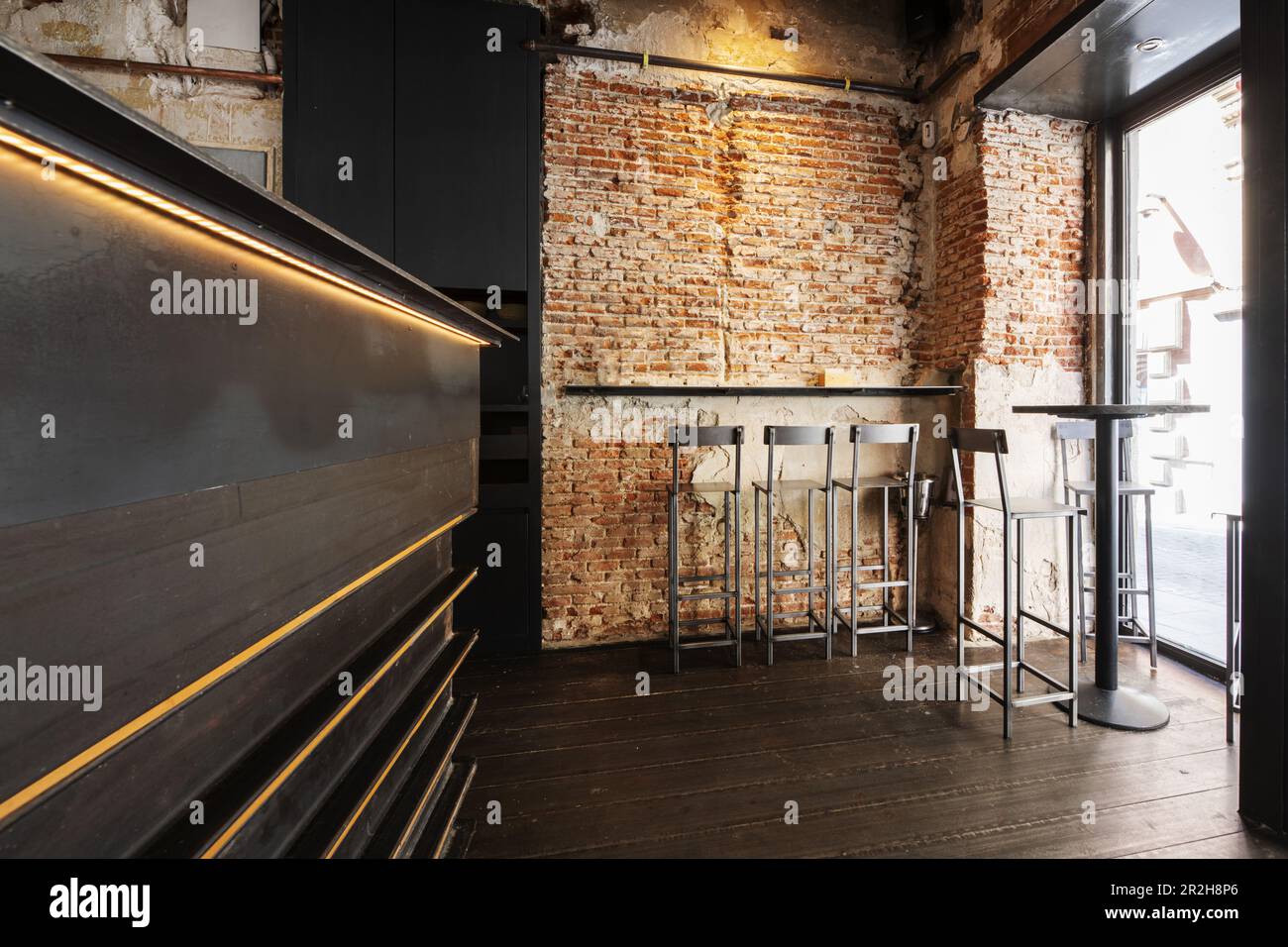 High tables and matching stools in a pub with exposed brick walls Stock ...