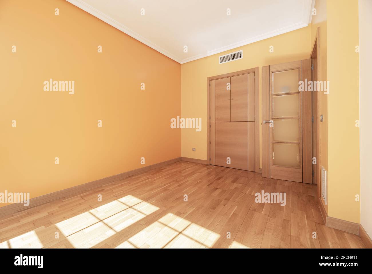 An empty room with an oak door with windows and a serving hatch with ...