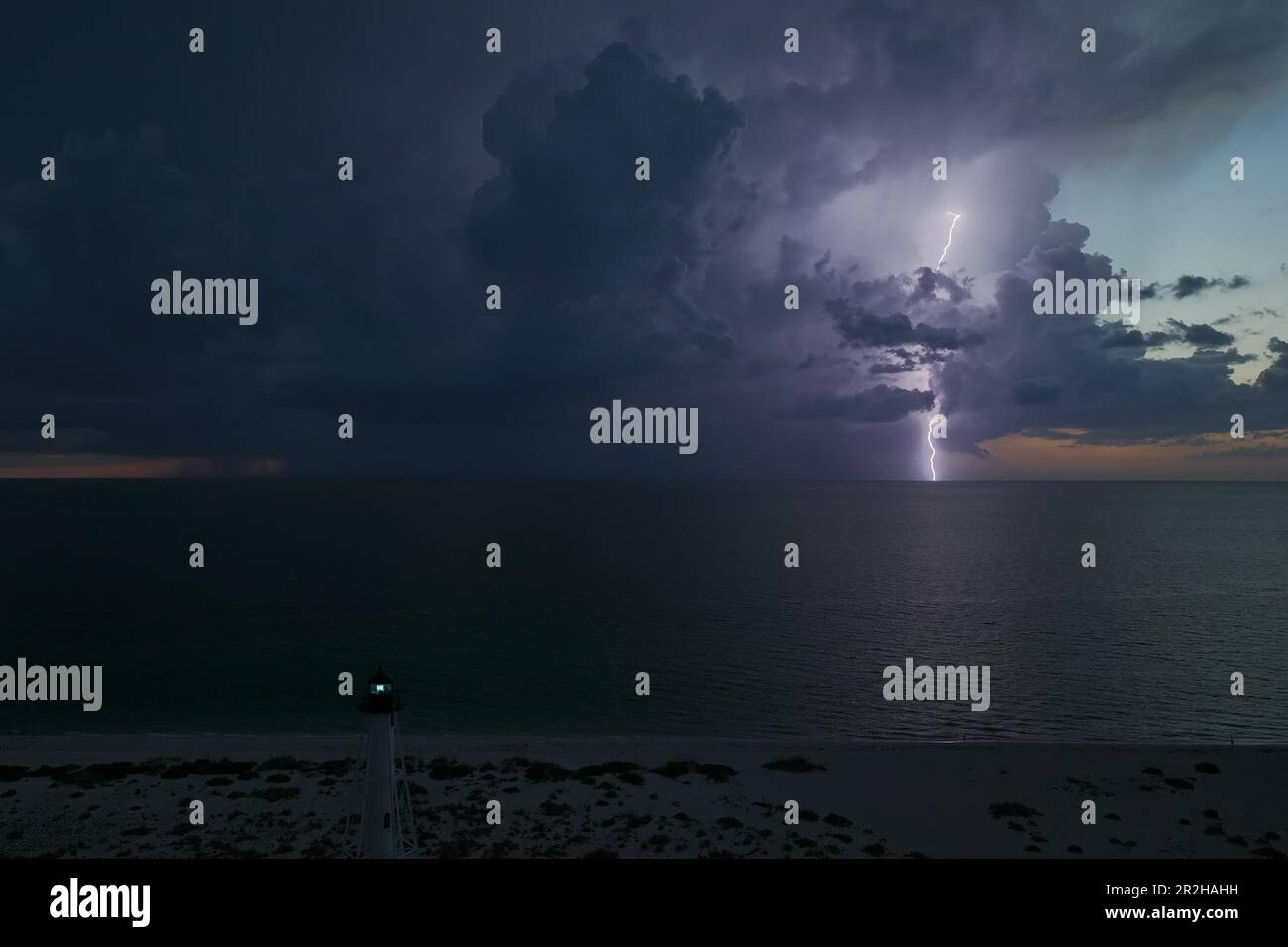 White tall lighthouse on sea shore with blinking light at stormy night ...