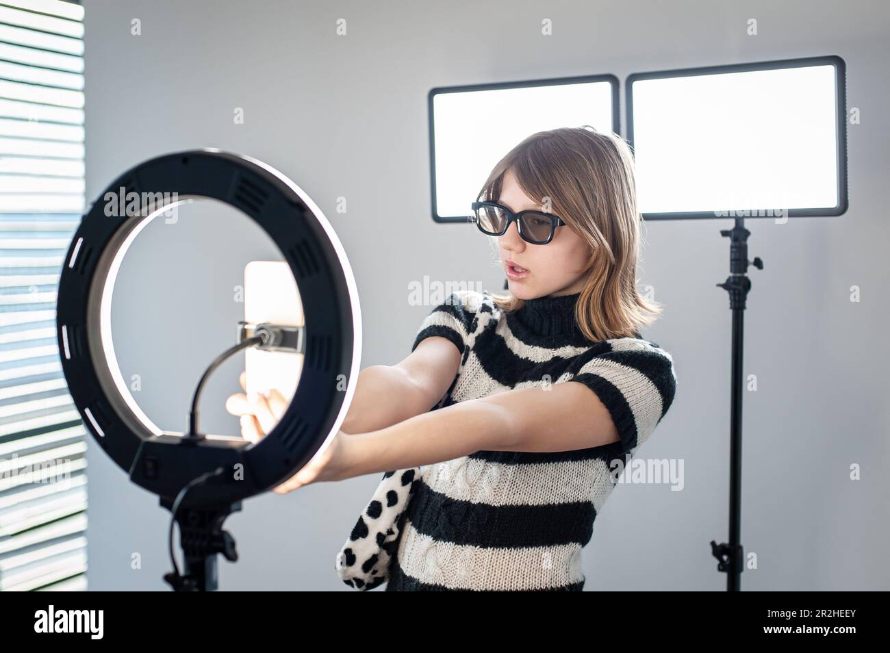 Influencer young woman recording video on smartphone and lighting ...