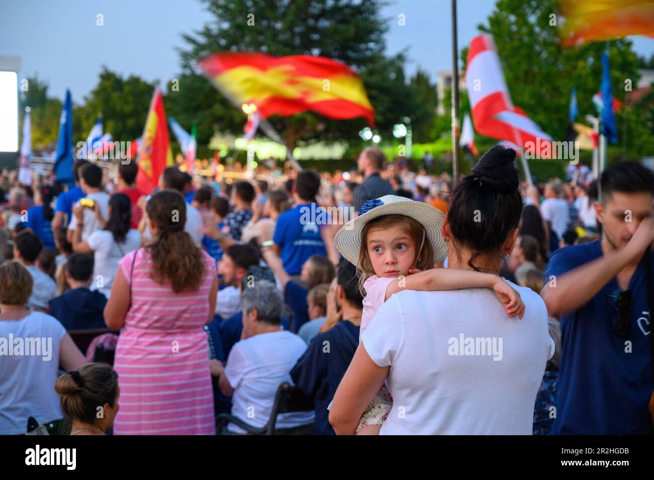 A little girl in mother's arms in a crowd of people. Holy Mass during ...