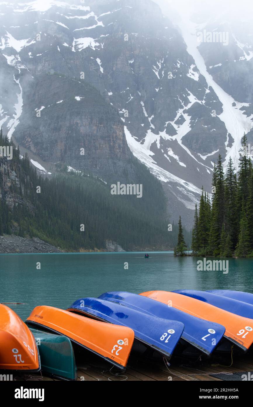 Canoes in turquoise Lake Louise with misty mountains in the background ...