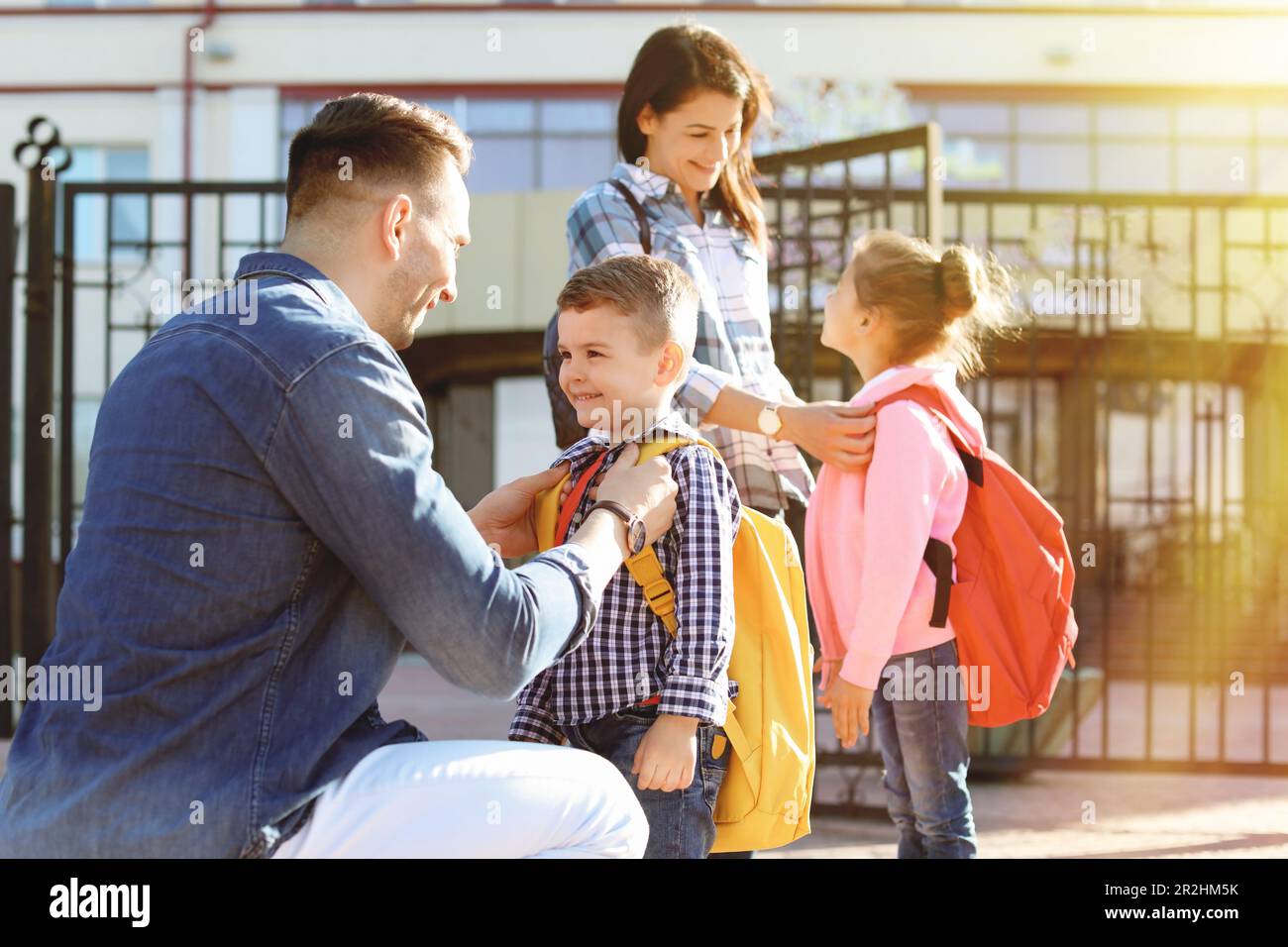Young parents saying goodbye to their little children near school Stock ...