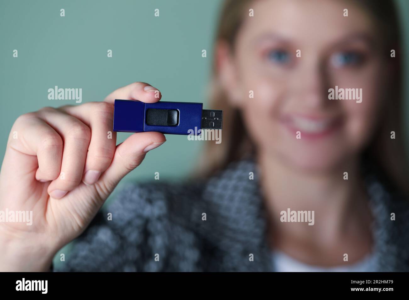Woman holding usb flash drive against green background, focus on hand ...