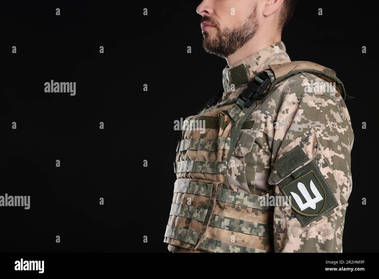 Soldier with Ukrainian trident on military uniform against black ...