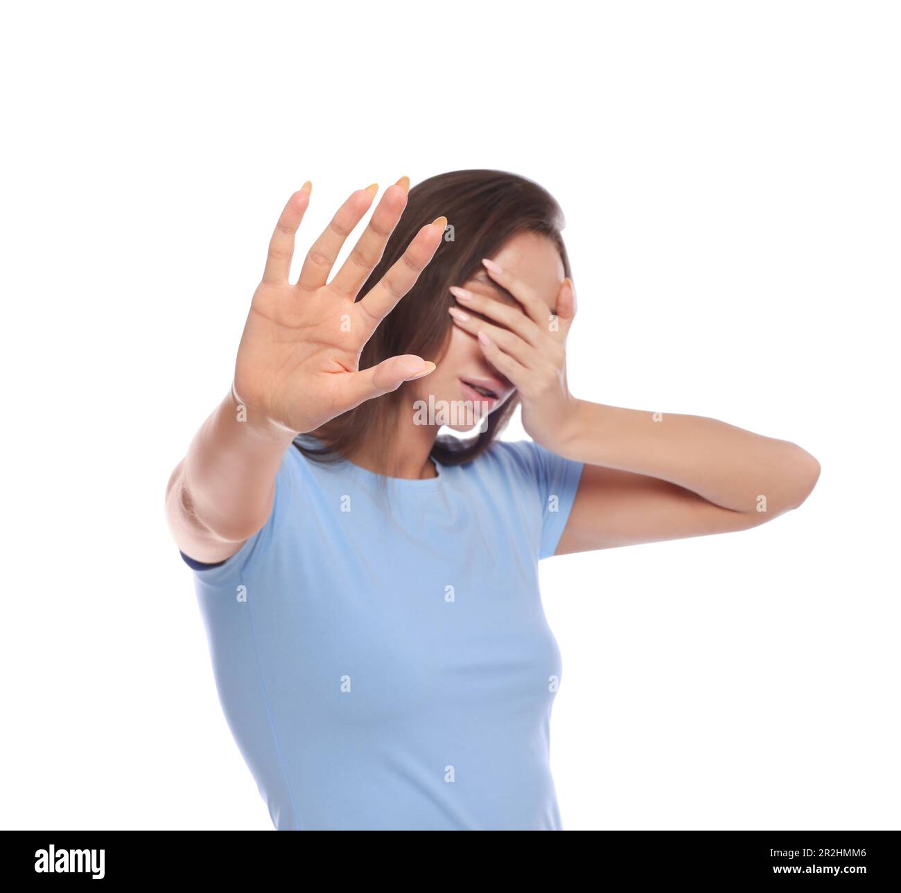 Embarrassed woman covering face against white background, focus on hand ...