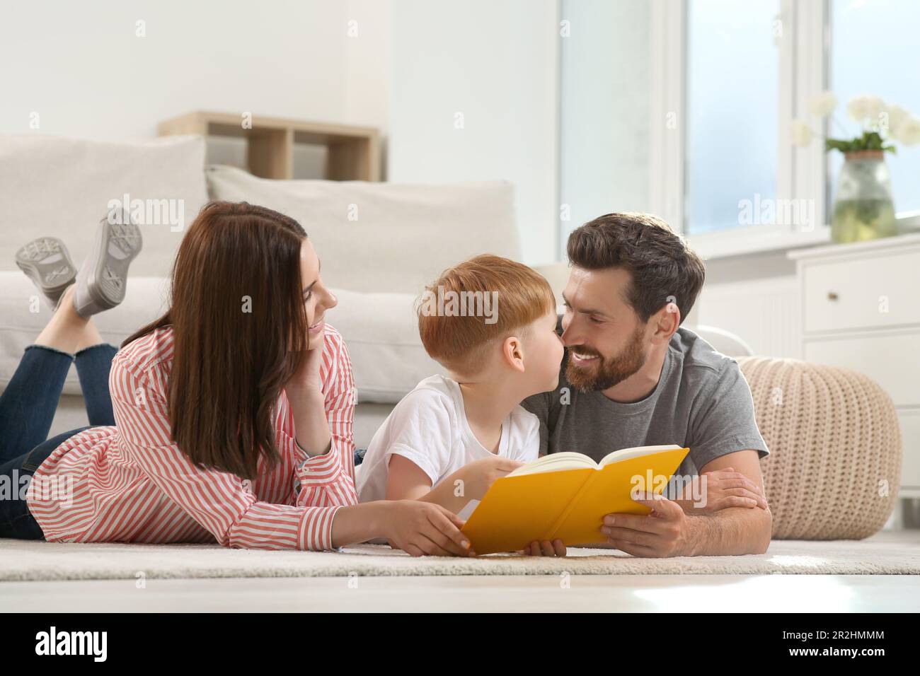 Happy parents with their child reading book on floor at home Stock ...