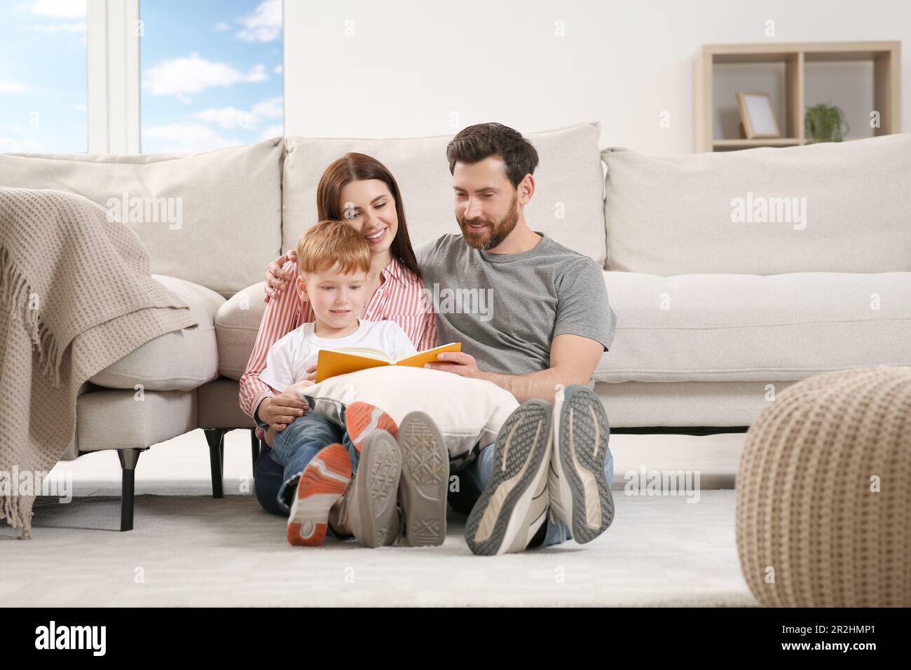 Happy parents with their child reading book on floor at home Stock ...